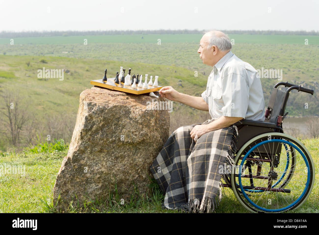 Handicapped pensioner playing chess outdoors sitting in his wheelchair ...
