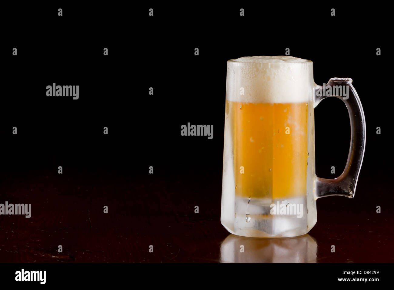 cold beer served in a frozen mug on a bar top isolated on a black ...