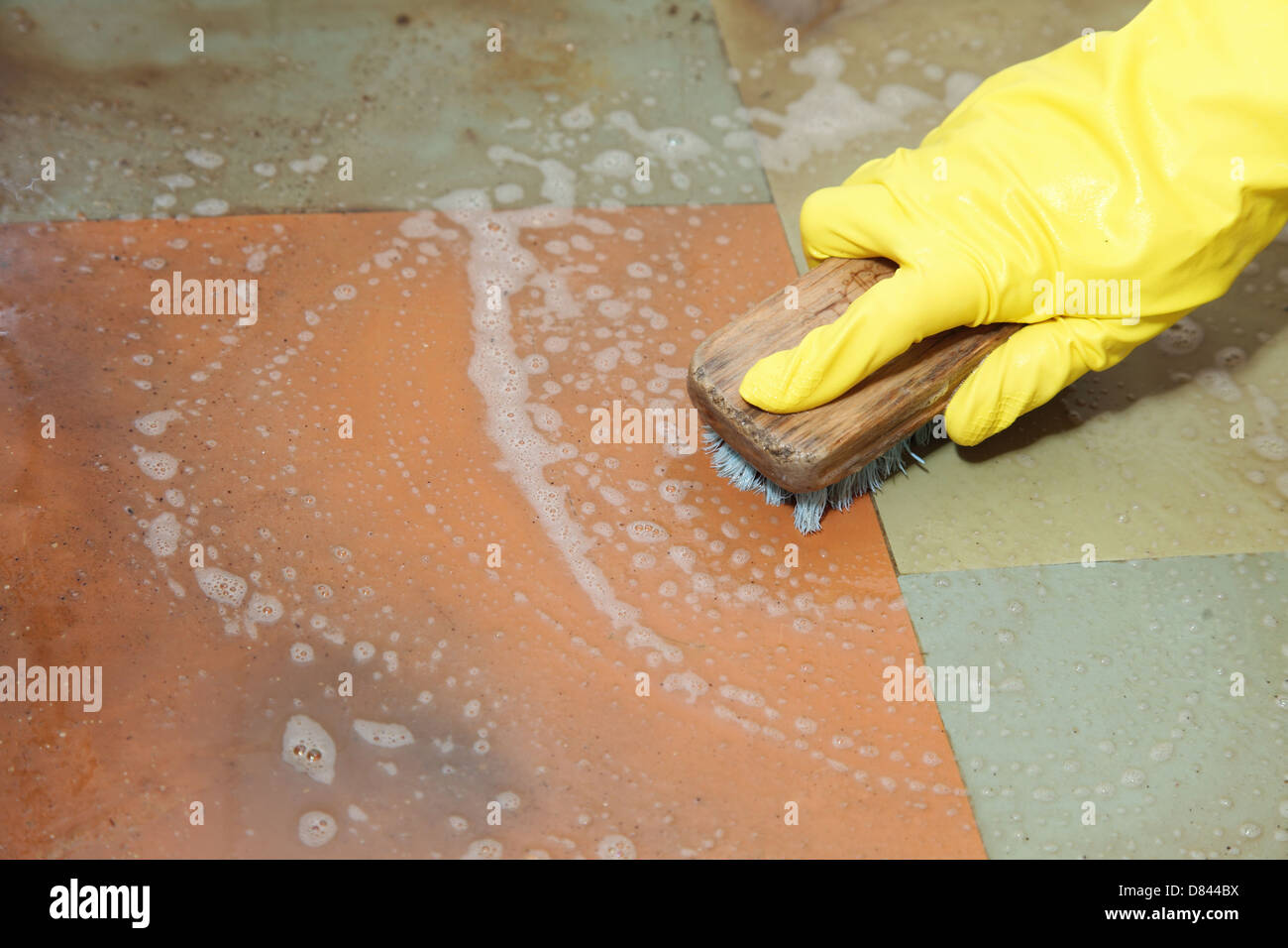 Hand in yellow glove cleaning dirty filthy floor with brush indoors ...