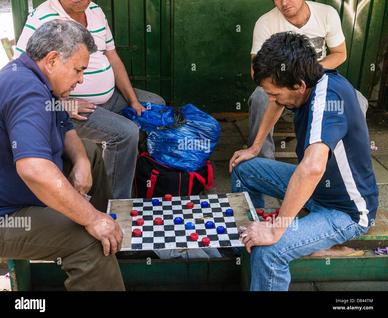 Two men play checkers as two others look on in the streets of Asunción ...