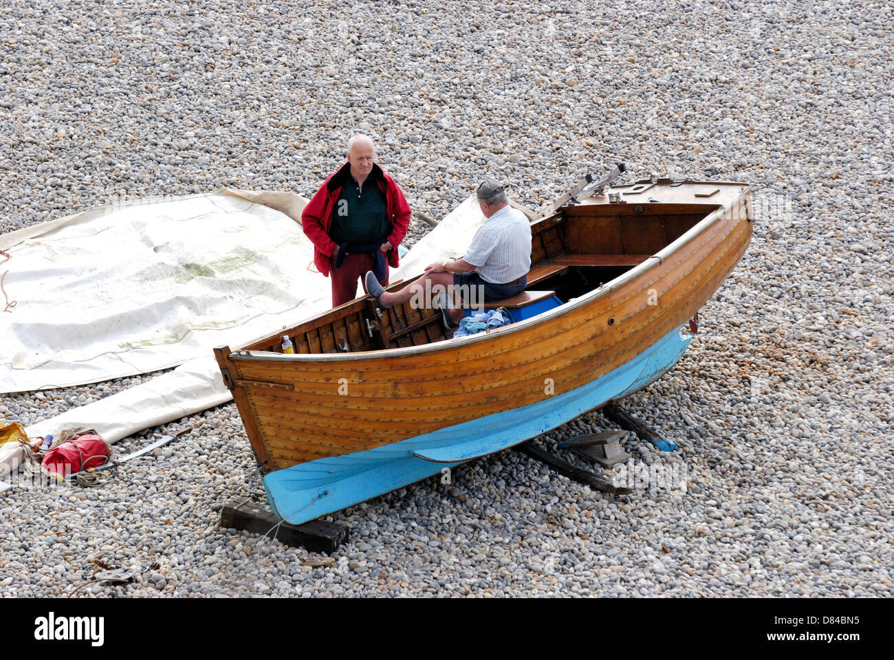 Two men by a rowing boat talking on the beach england uk Stock Photo ...