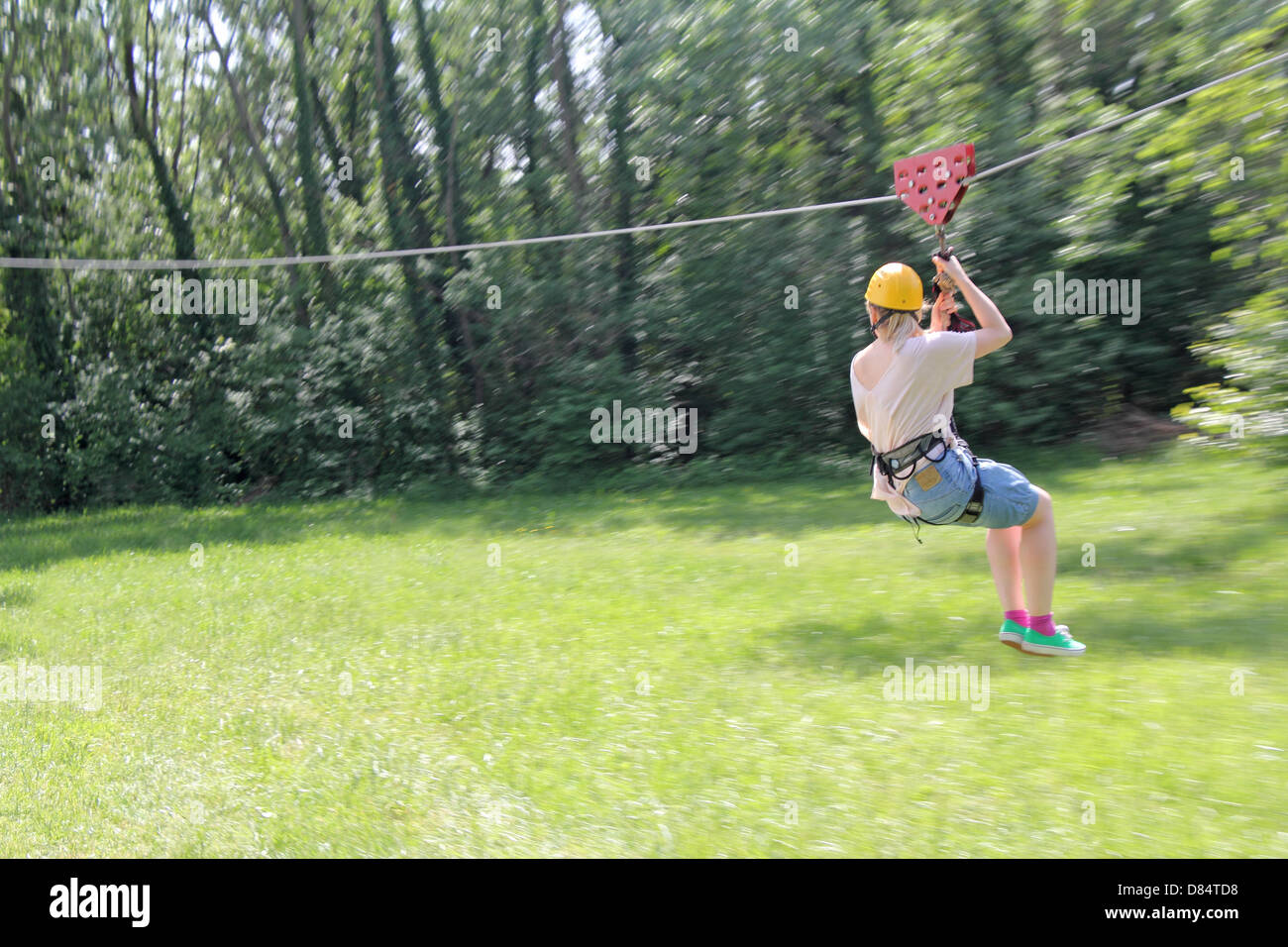 A female climber crosses the meadows along a tyrolean traverse Stock ...