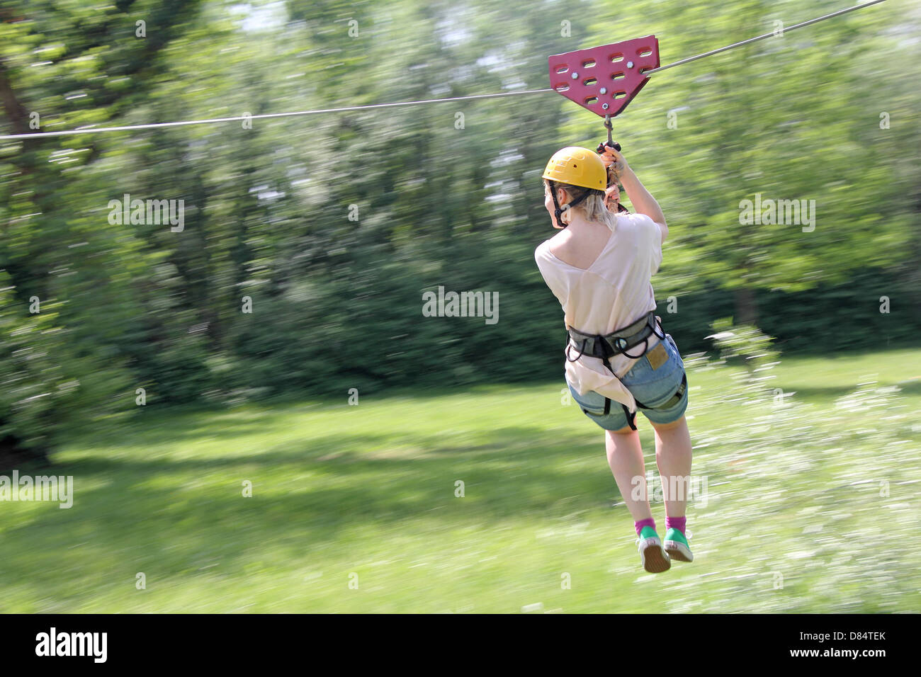 A female climber crosses the meadows along a tyrolean traverse Stock ...