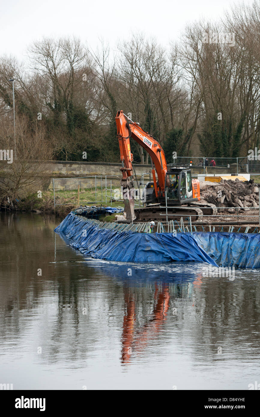 A mechanical excavator with a hydraulic hammer attachment at work on a ...