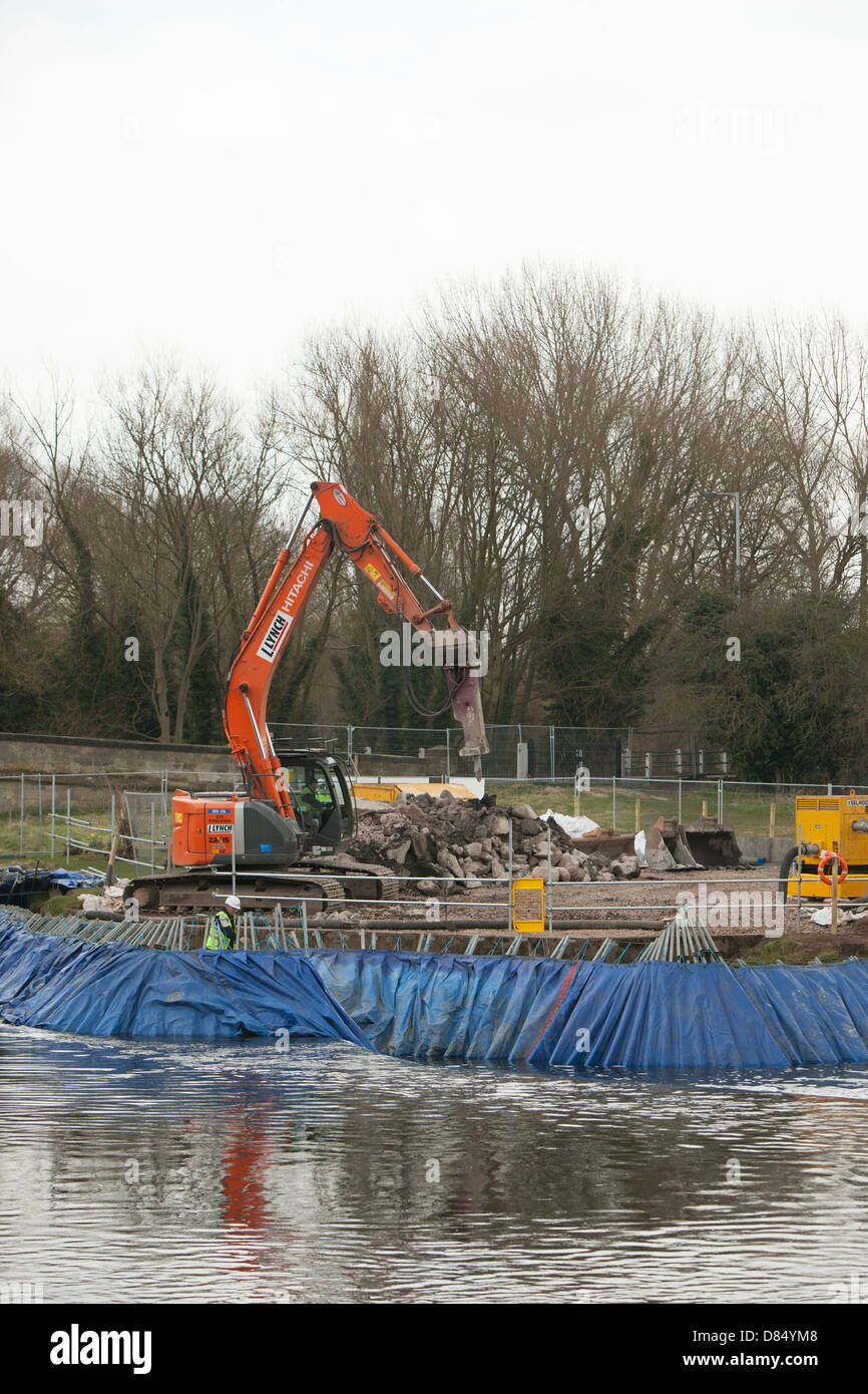 A mechanical excavator with a hydraulic hammer attachment at work on a ...