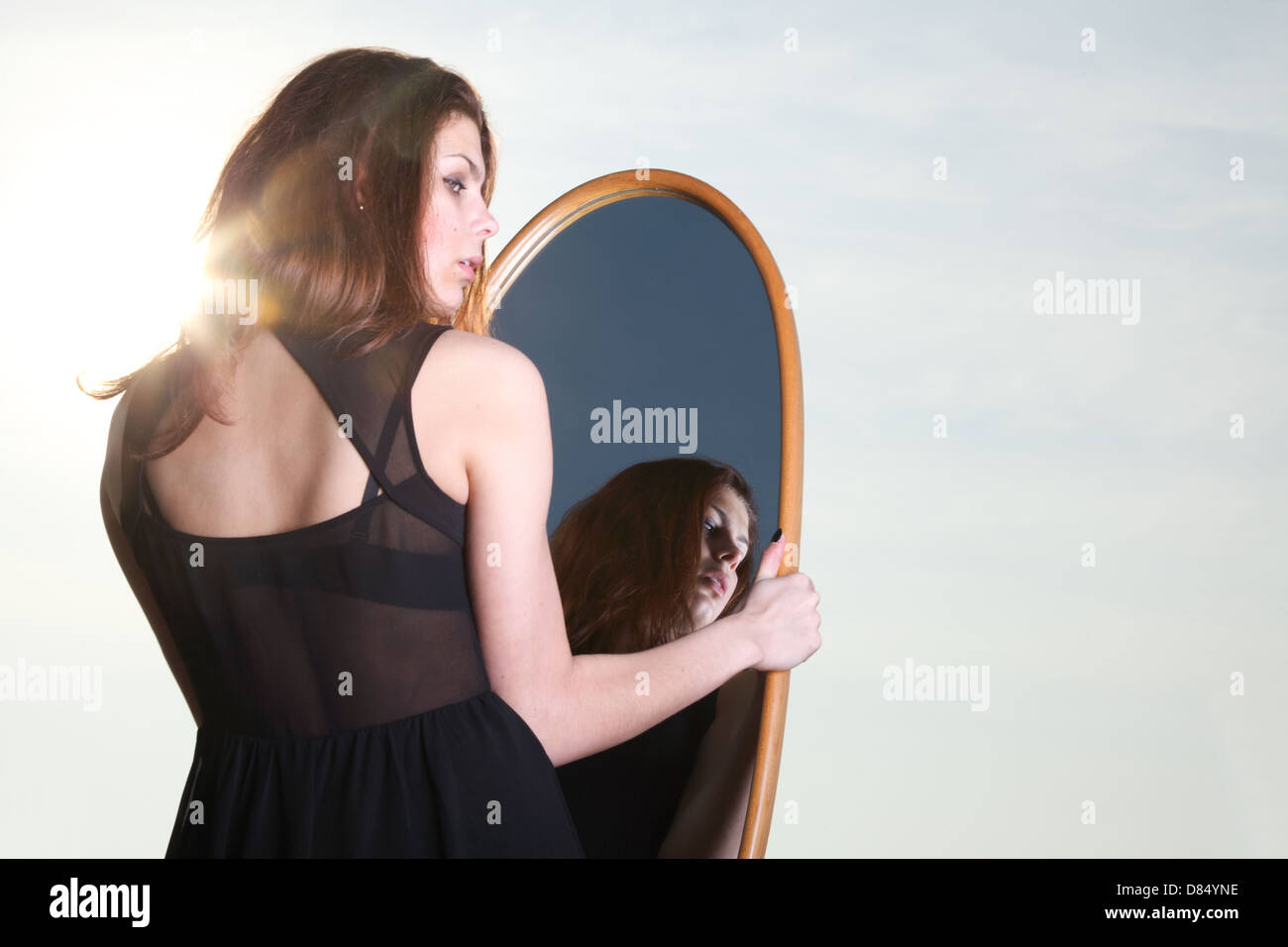 thoughtful young woman looks at the reflection in the mirror - solitude ...