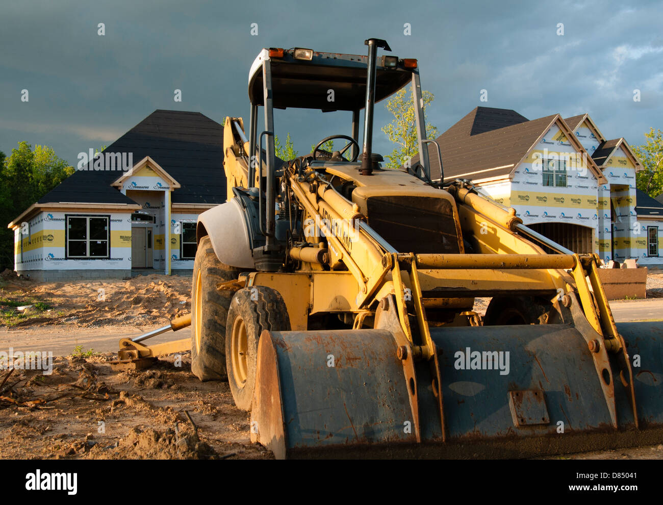 Backhoe in front of new residential homes under construction Stock ...
