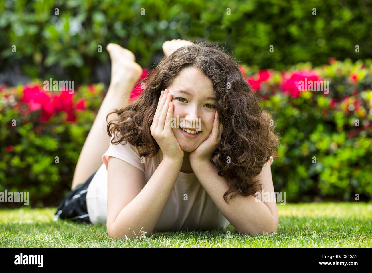Horizontal Photo of young girl lying down on the grass with flowering ...