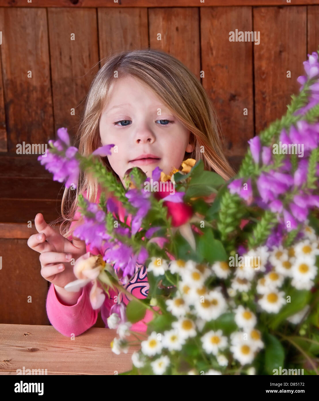 4 Year Old Girl Is Behind A Cut Flower Bouquet Arranging The Flowers 4-year-old-girl-is-behind-a-cut-flower-bouquet-arranging-the-flowers