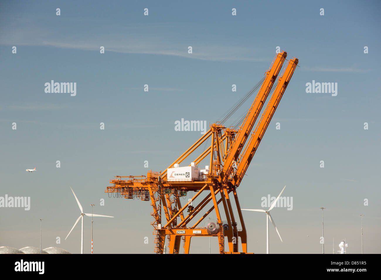 A plane flying past dock side cranes in Amsterdam, Netherlands, with ...