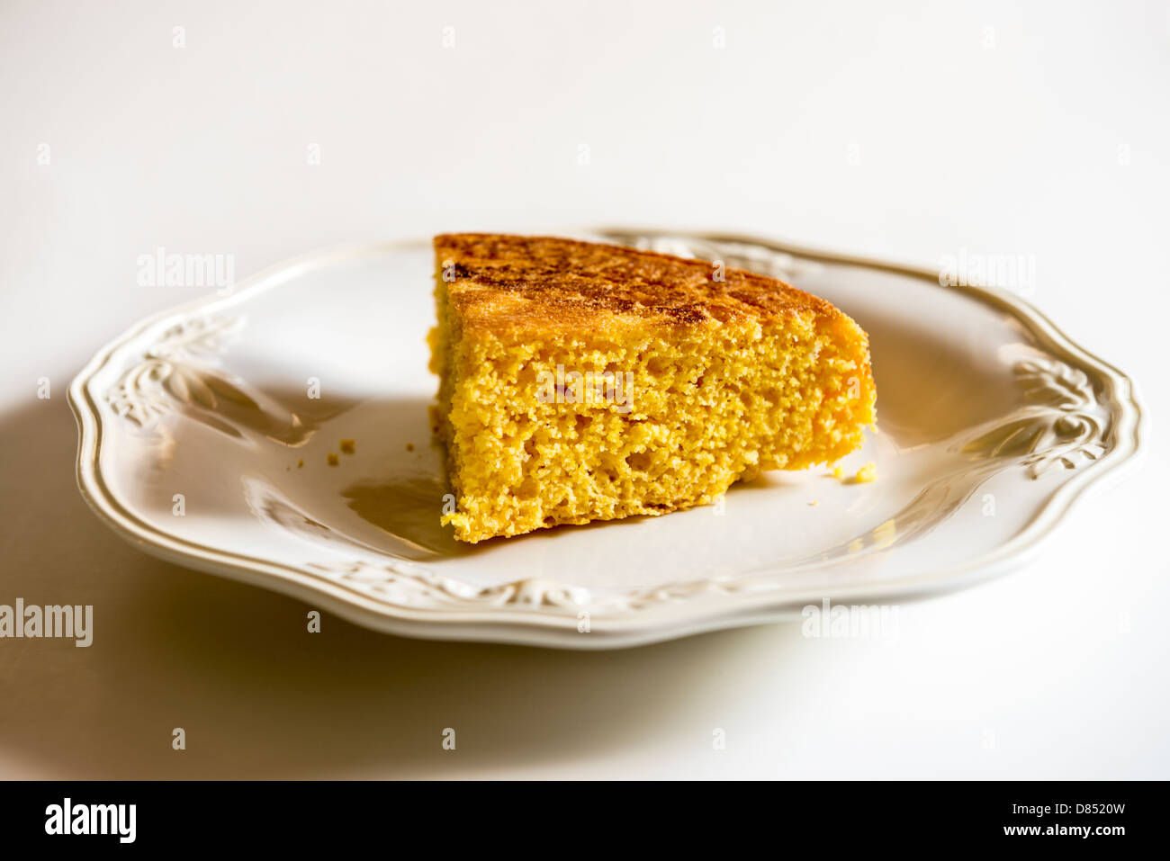 A slice of homemade cornbread on a white plate with white background ...