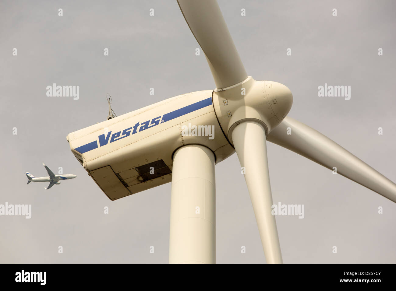 A wind turbine in Amsterdam with a plane flying past having taken off ...