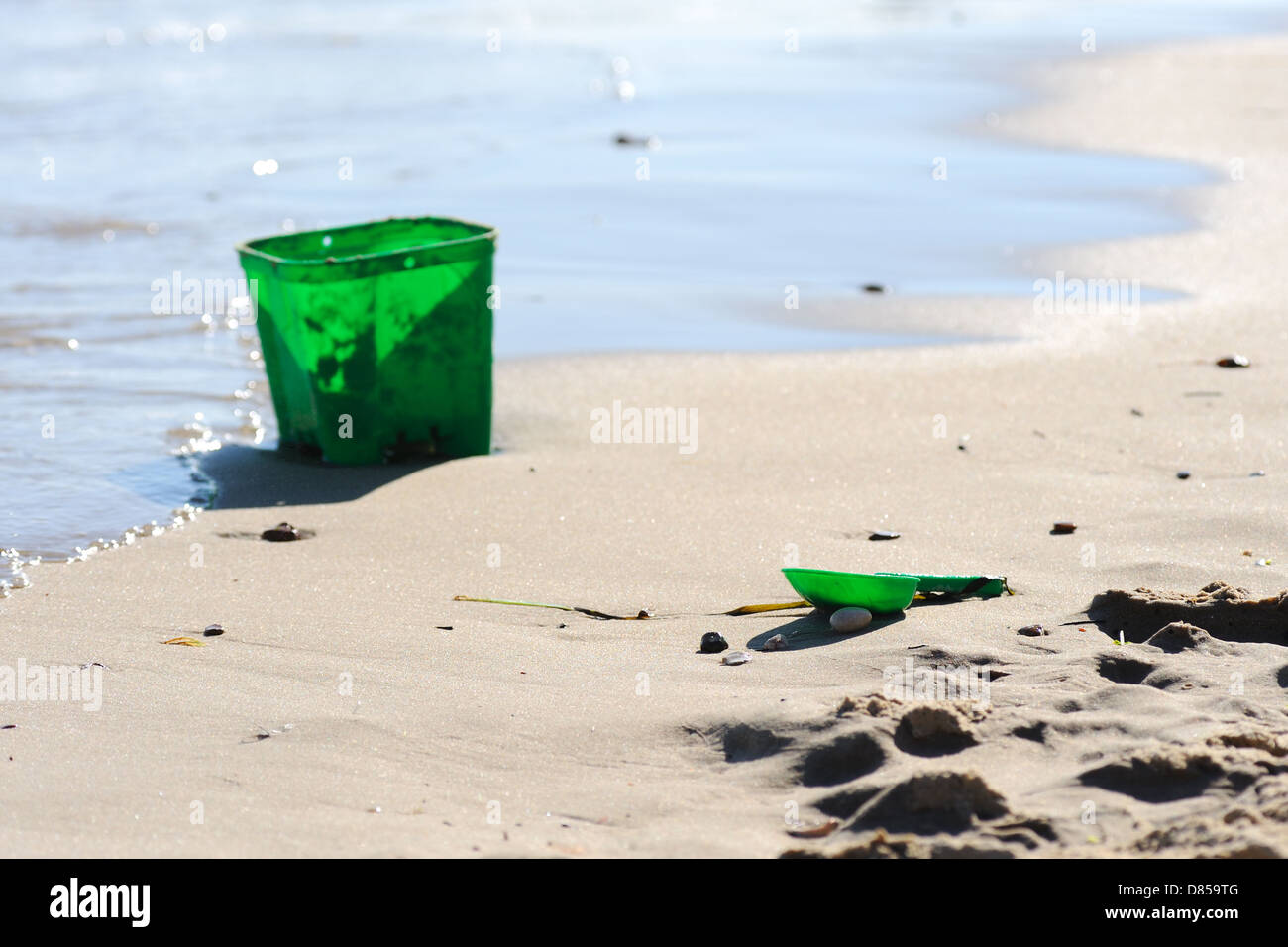 Green bucket and spade disgarded on beach Stock Photo - Alamy