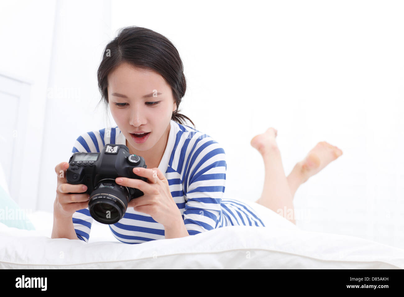 young woman lying on bed holding camera Stock Photo - Alamy