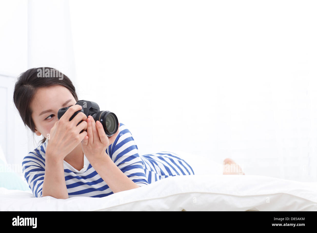 young woman lying on bed holding camera Stock Photo - Alamy