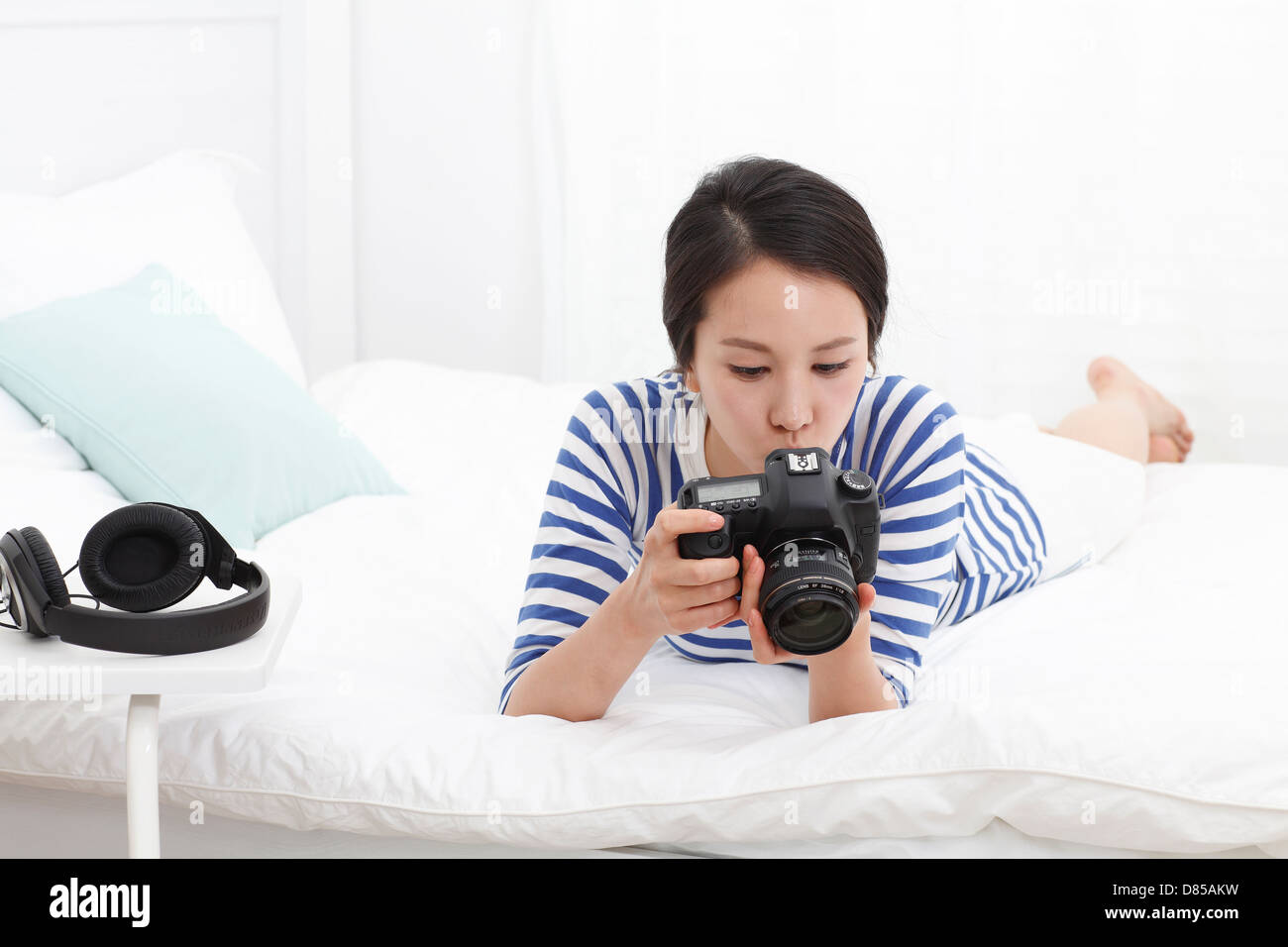 young woman lying on bed holding camera Stock Photo - Alamy