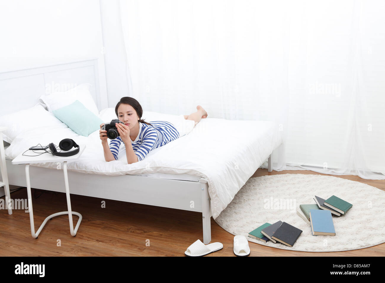 young woman lying on bed holding camera Stock Photo - Alamy