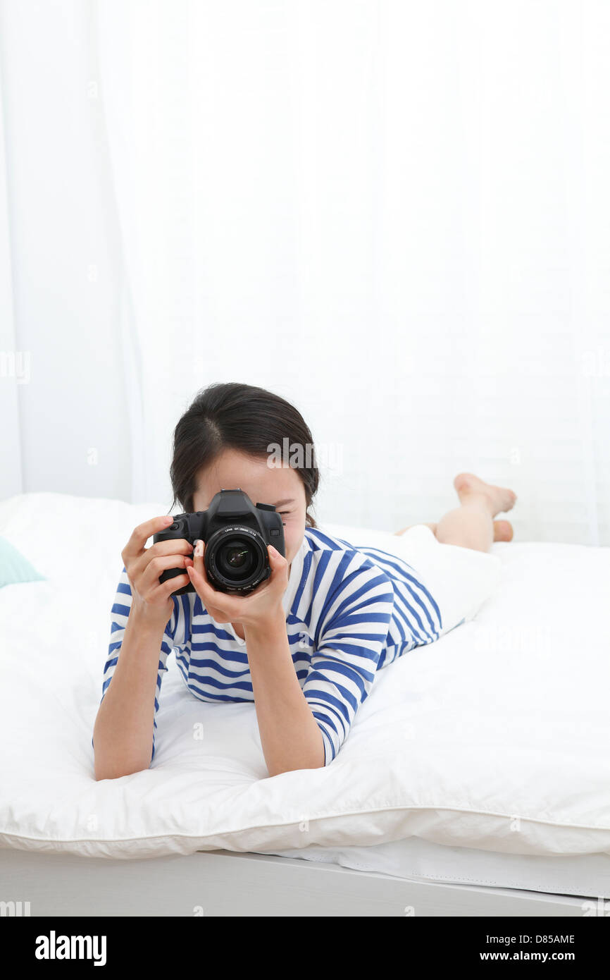 young woman lying on bed holding camera Stock Photo - Alamy