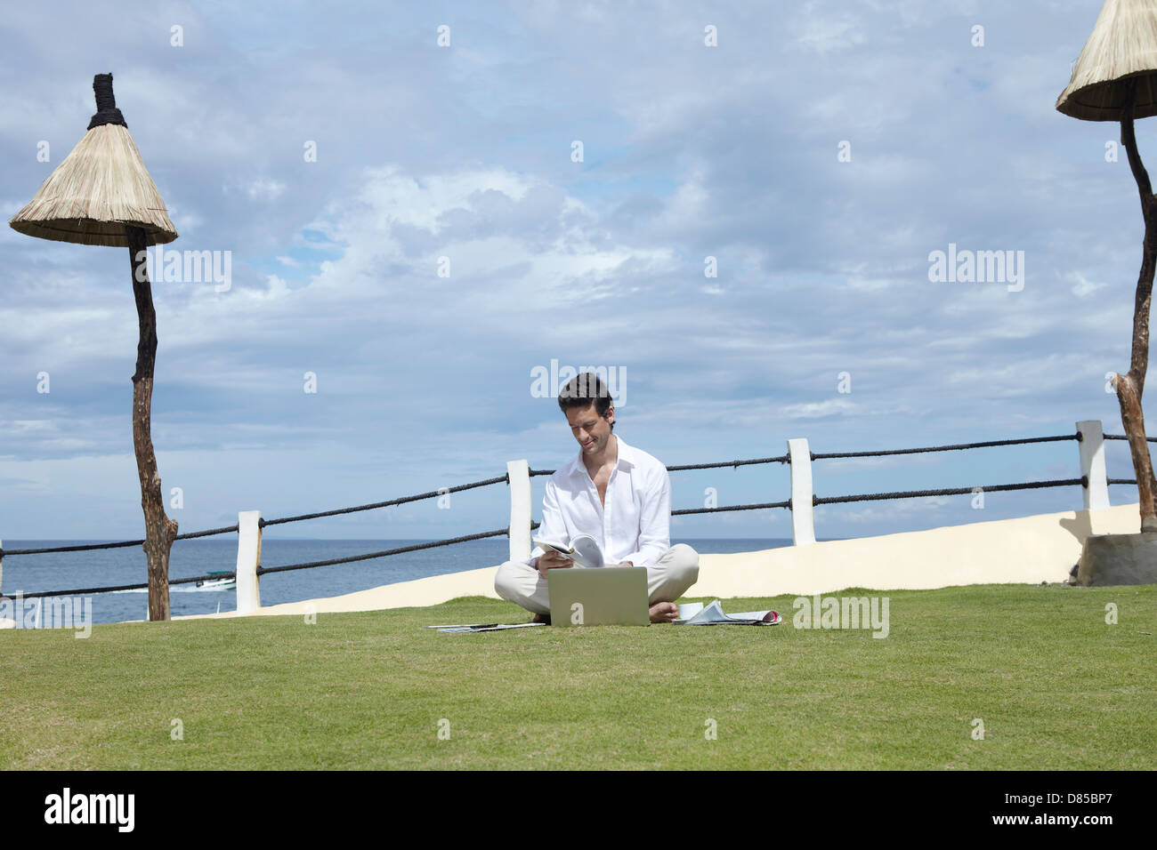 man sitting cross-legged on grass working on laptop Stock Photo - Alamy