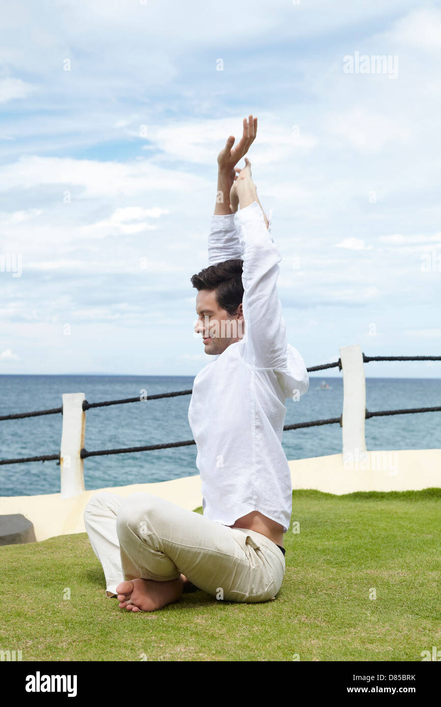 man sitting cross-legged his arms raised Stock Photo - Alamy