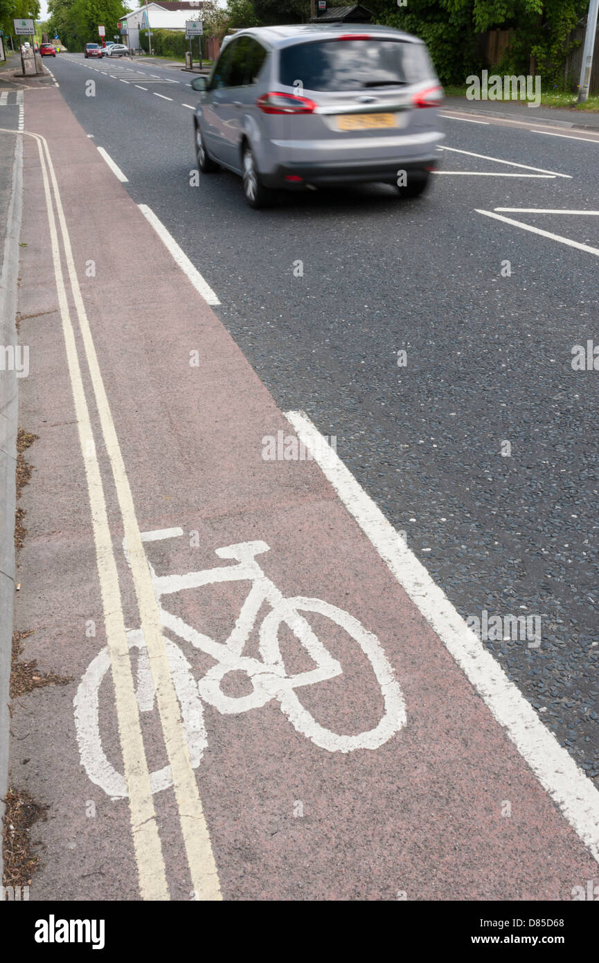 A cycle lane at the side of a road with cycling sign with cars passing ...