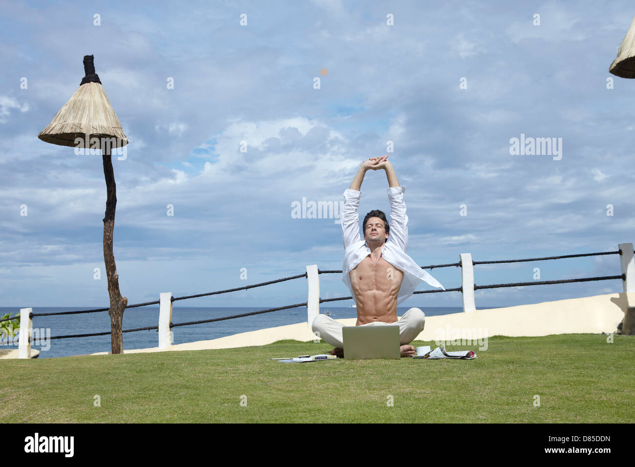 man sitting cross-legged on grass stretching Stock Photo - Alamy