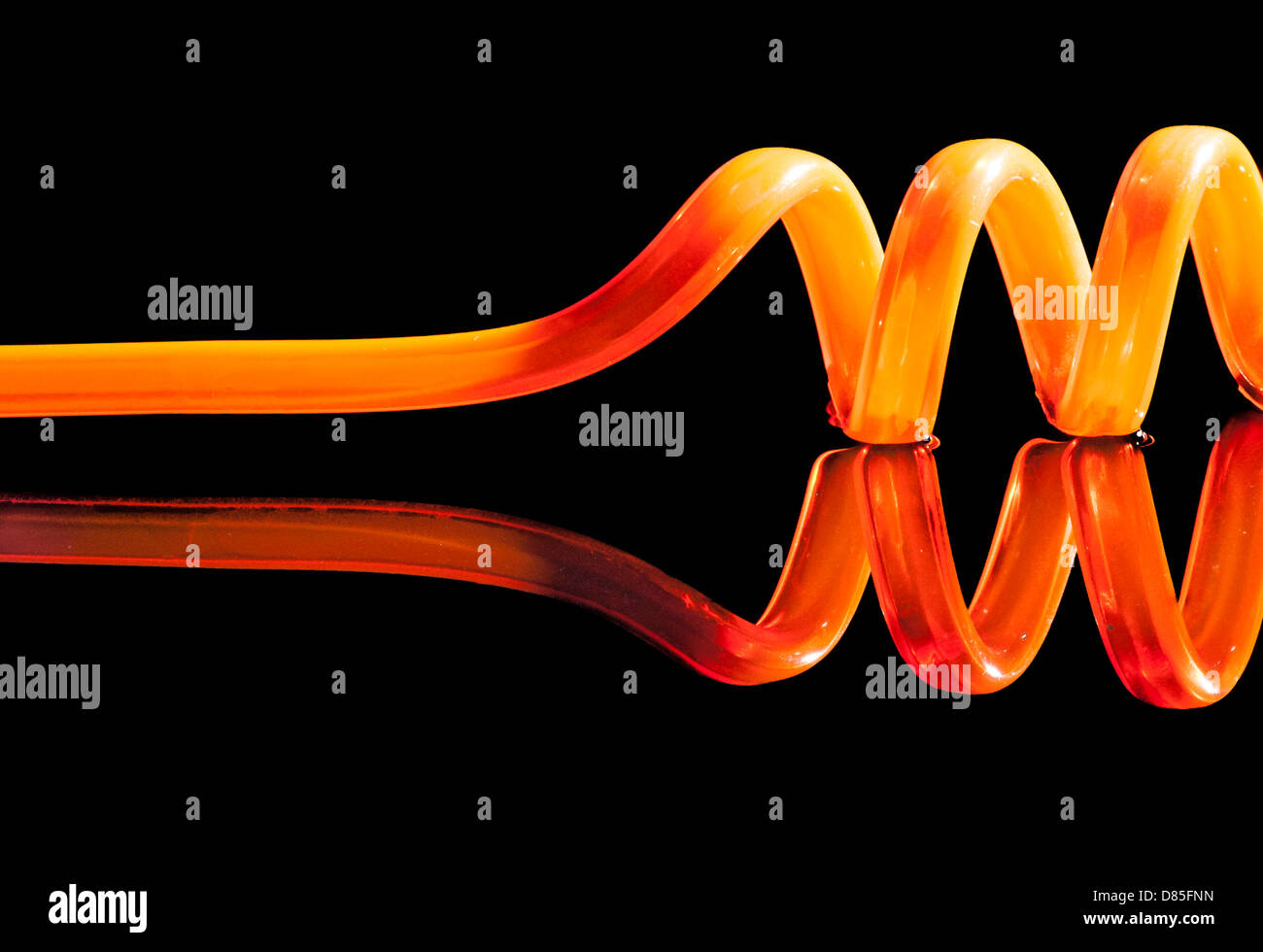 Part of a large coiled orange straw laying horizontally on some water ...