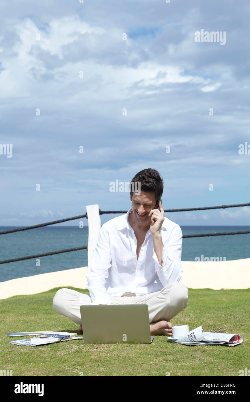 man sitting on grass working on laptop Stock Photo - Alamy