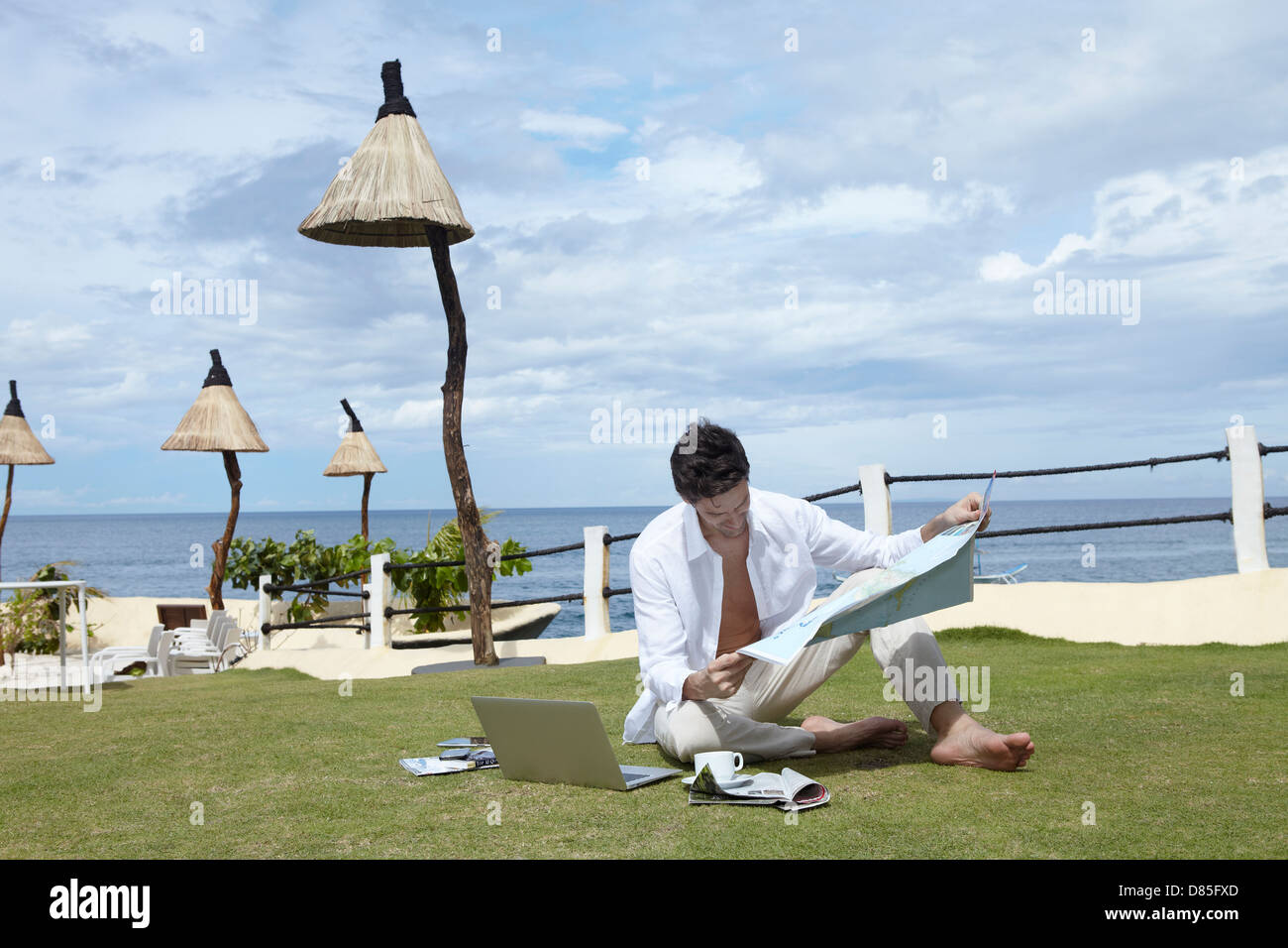 man sitting on grass looking map Stock Photo - Alamy