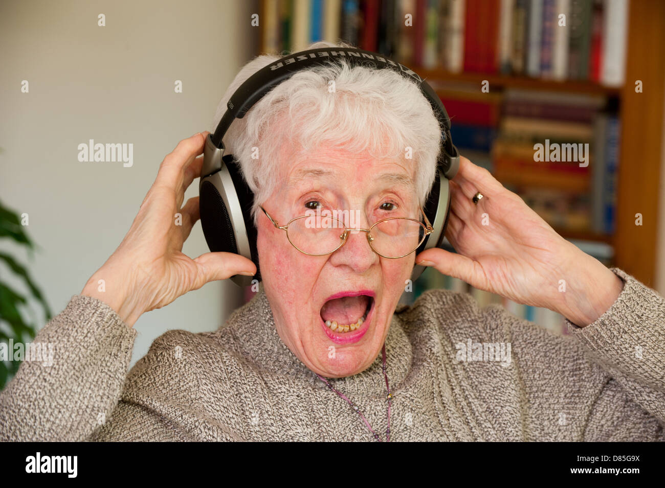 An elderly woman wearing outer ear headphones Stock Photo - Alamy