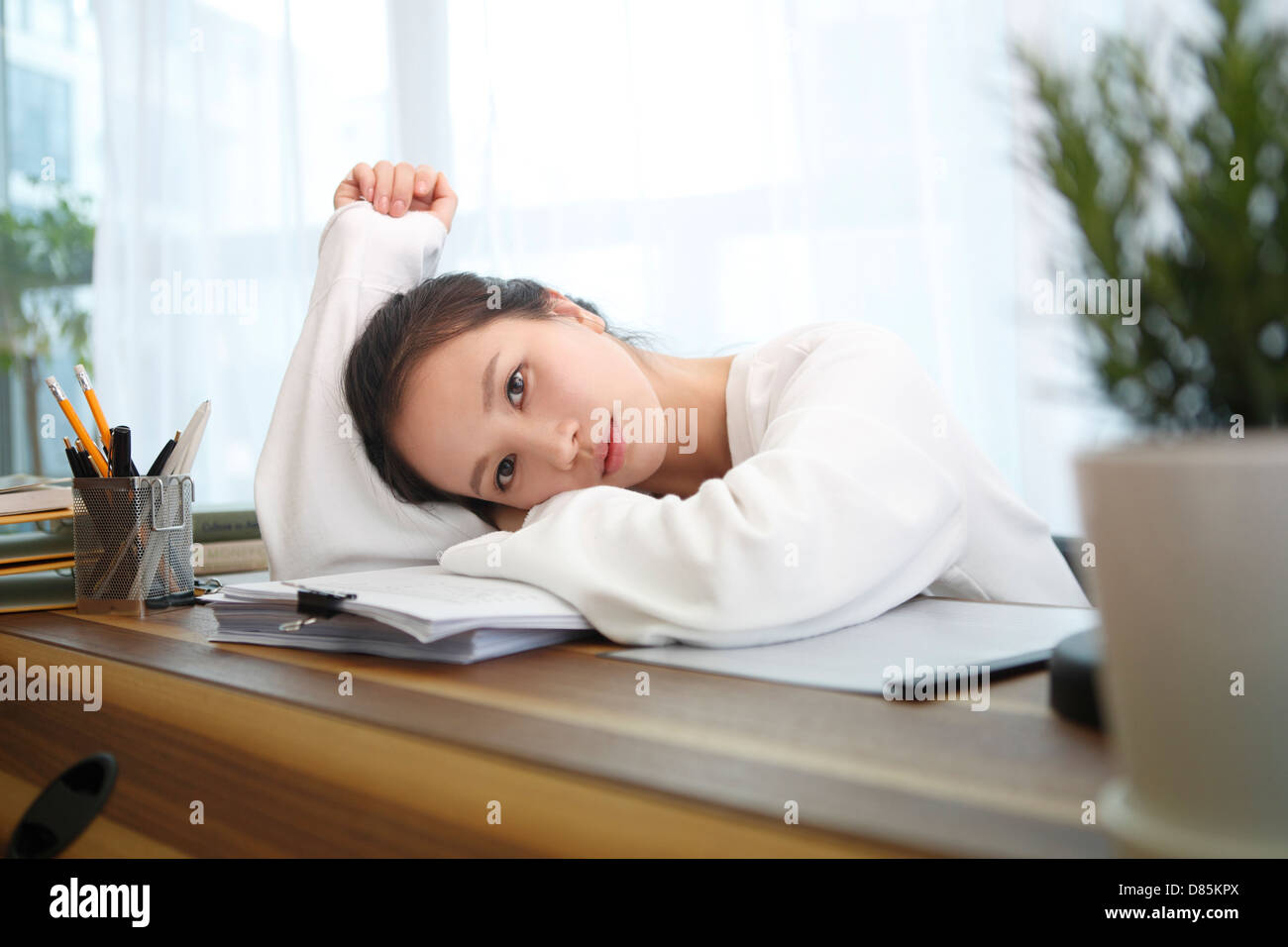 young woman resting her head on desk Stock Photo - Alamy