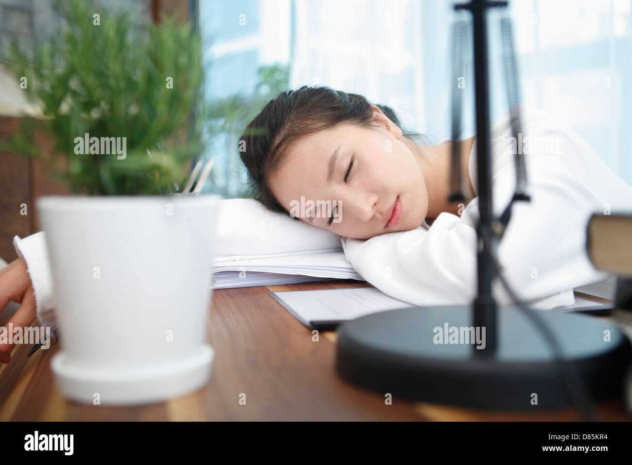 young woman resting her head on desk Stock Photo - Alamy