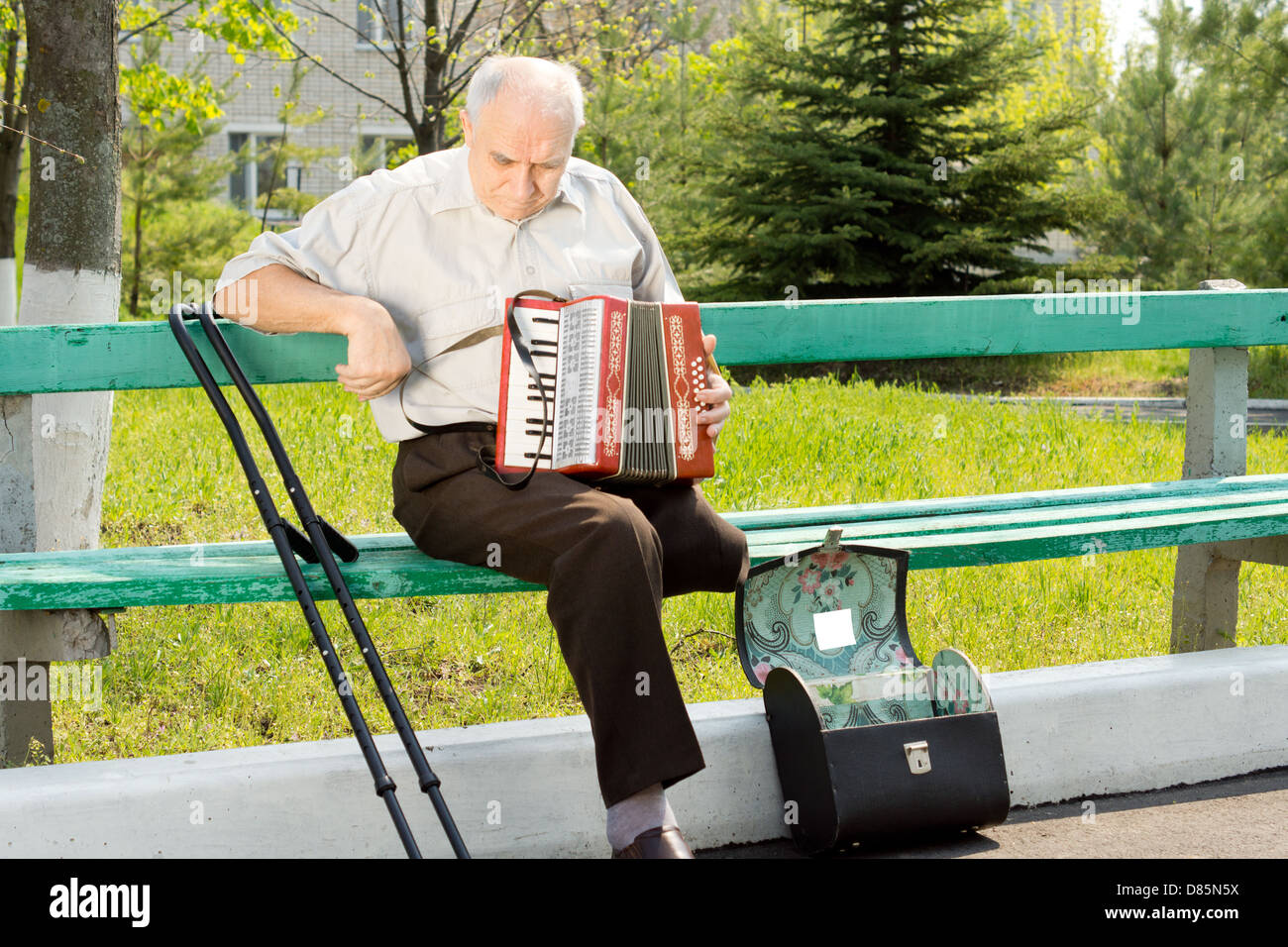 Handicapped senior man sitting on a park bench in the sunshine with an ...
