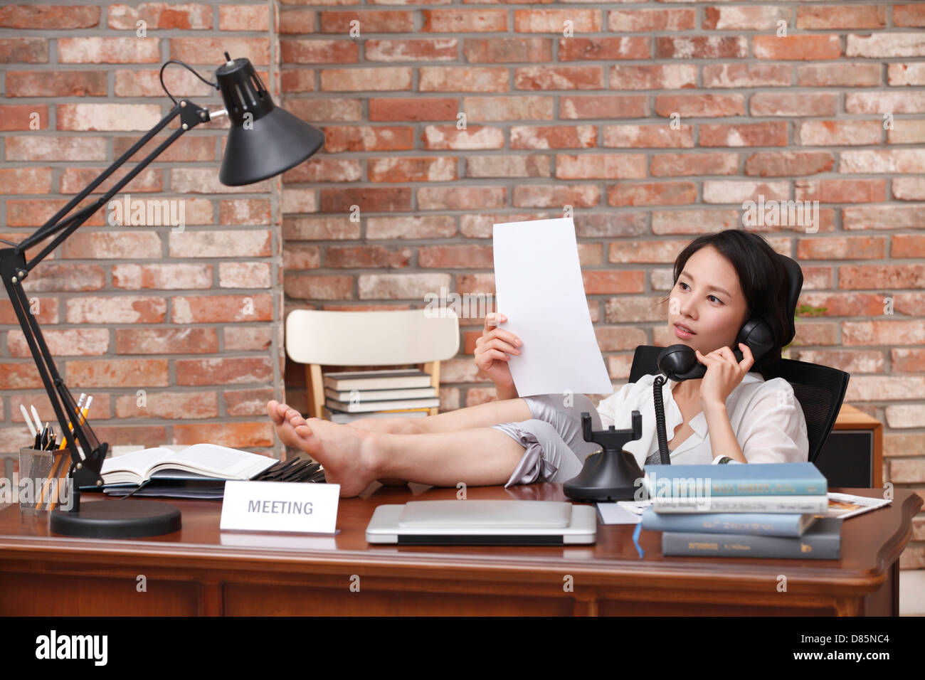 young woman sitting desk talking on telephone Stock Photo - Alamy