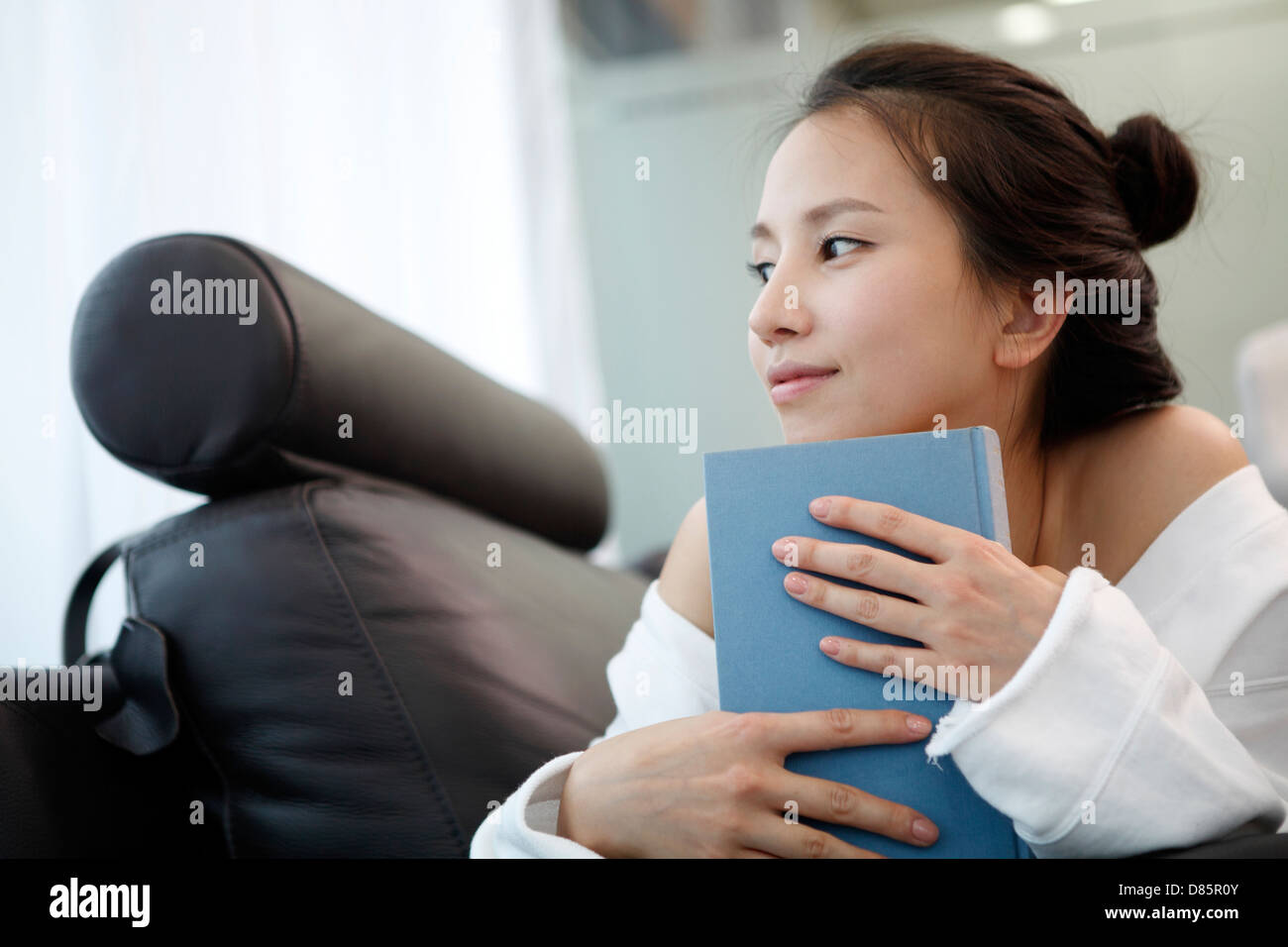 young woman lying on her front on sofa Stock Photo - Alamy