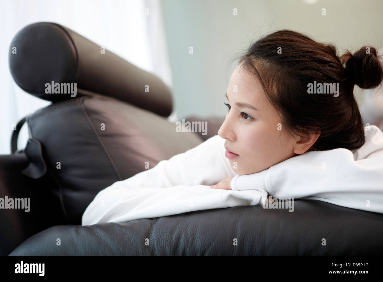 young woman lying on her front on sofa Stock Photo - Alamy