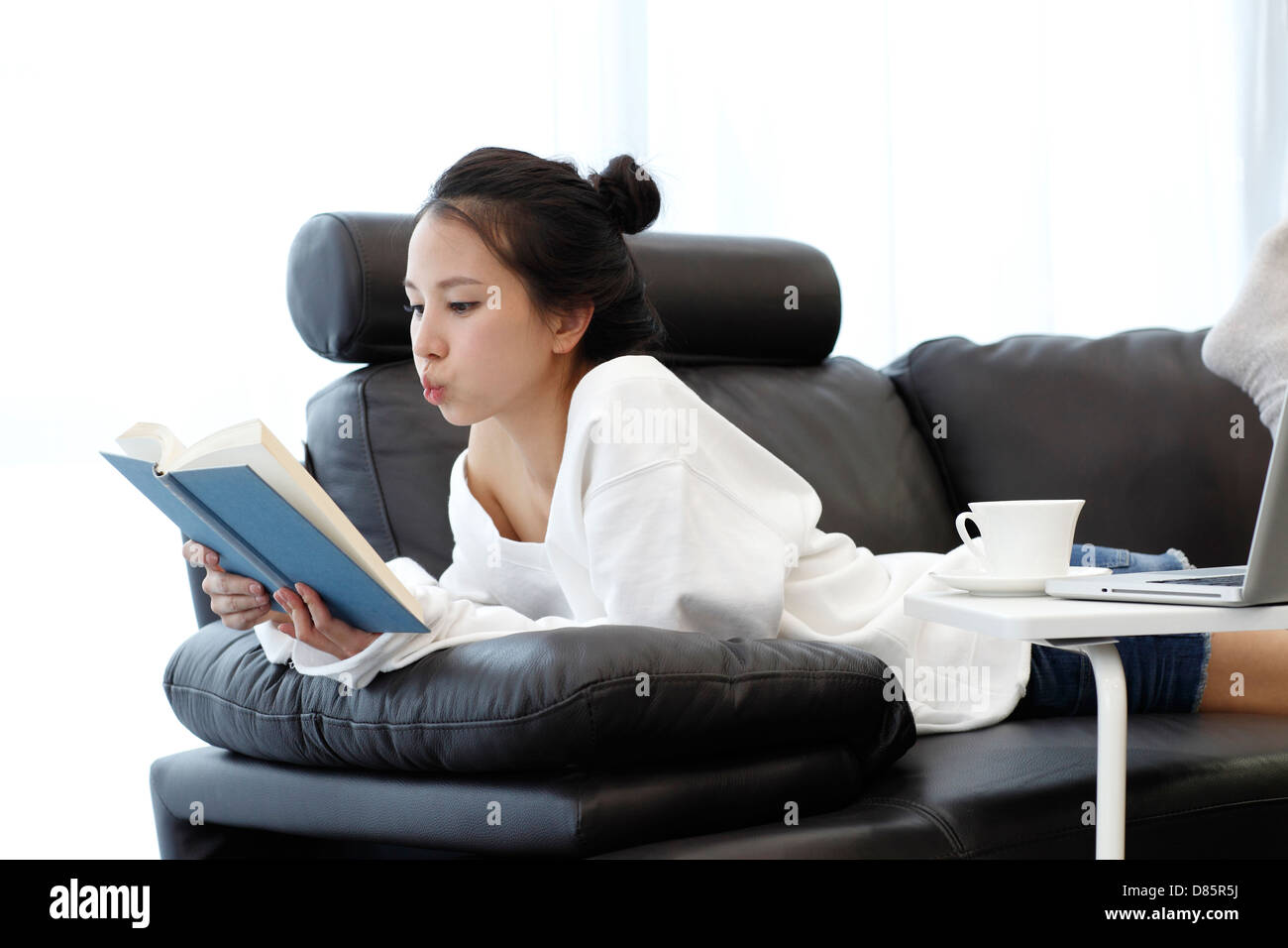 young woman lying on her front on sofa Stock Photo - Alamy