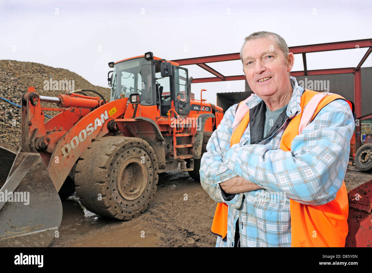 A construction worker beside his digger at a recycling centre Stock ...