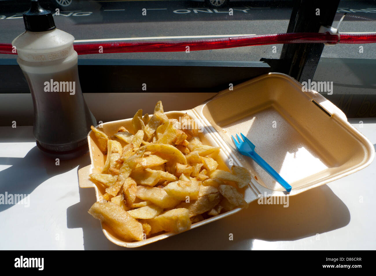A polysyrene tray of french fries and bottle of vinegar in a fish ...
