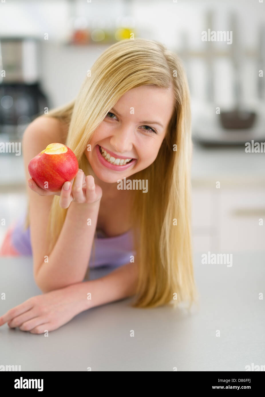 Happy teenager girl eating apple in kitchen Stock Photo - Alamy