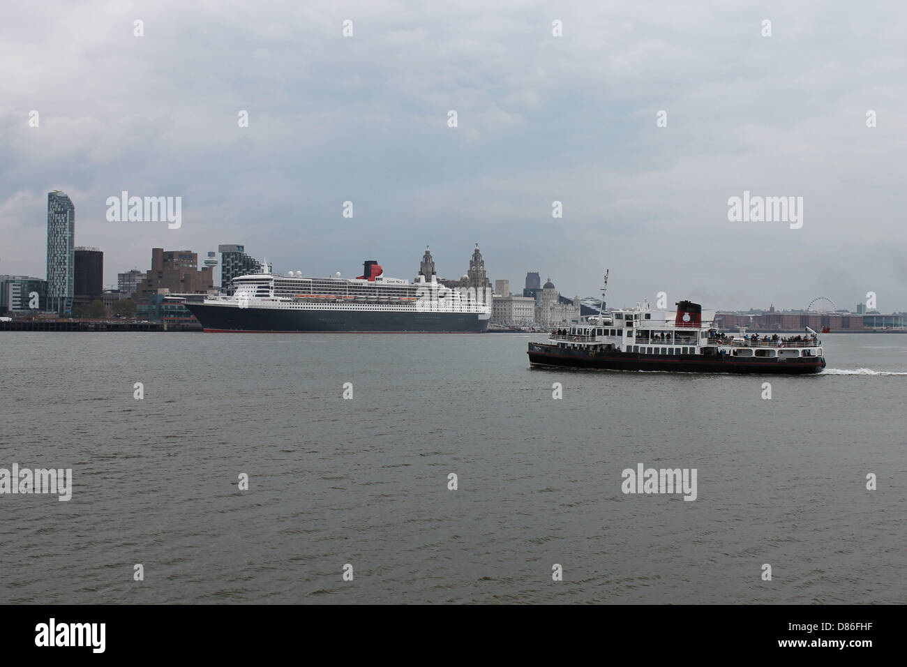 Queen Mary 2 docked in Liverpool on the river Mersey and ferry leaving ...