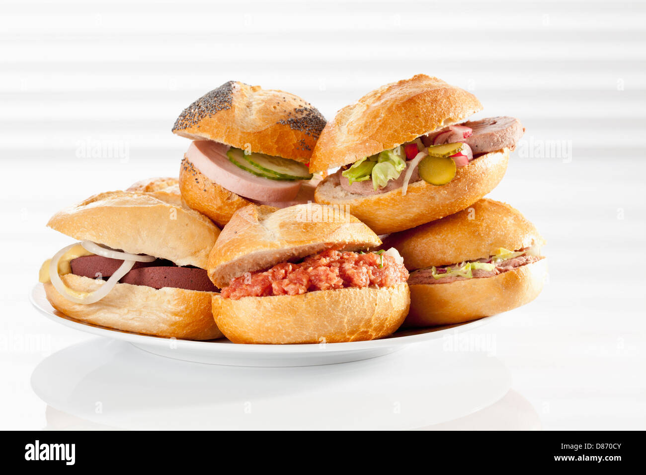 Variety of bread rolls sandwiches with mixed cold cuts on plate, close ...