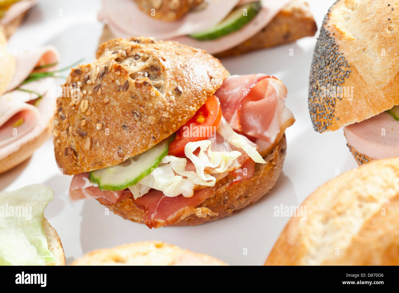 Variety of bread rolls sandwiches with mixed cold cuts on white ...