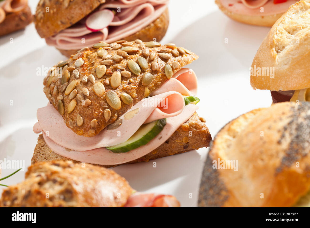 Variety of bread rolls sandwiches with mixed cold cuts on white ...