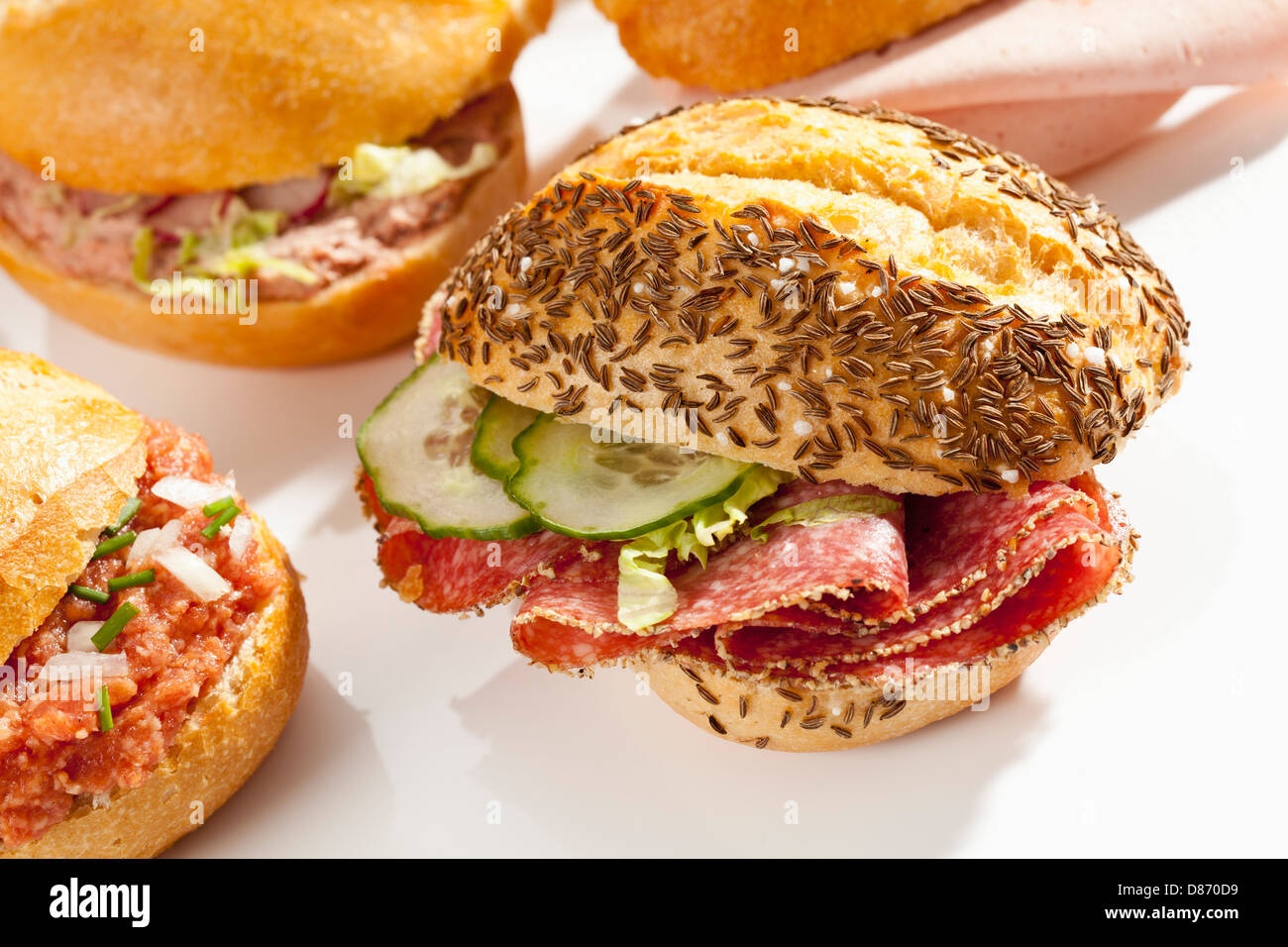 Variety of bread rolls sandwiches with mixed cold cuts on white ...
