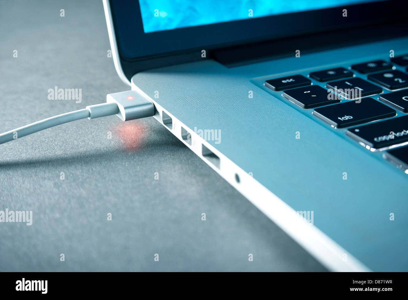 Laptop connected to battery charger Stock Photo - Alamy