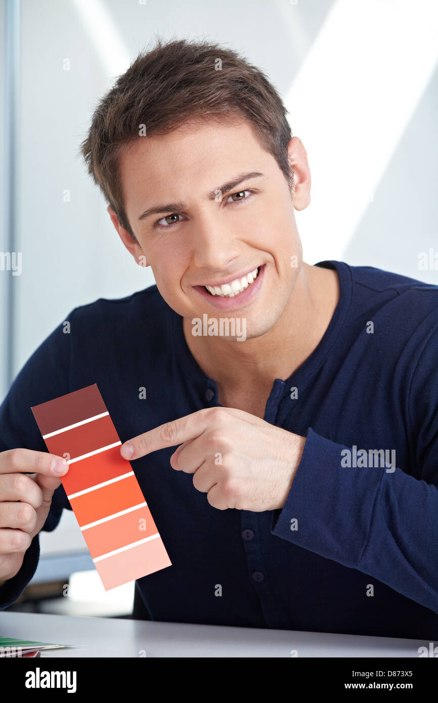 Smiling graphic designer with red color samples in his office Stock ...