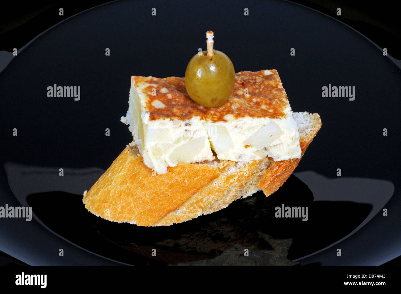 Spanish tortilla tapa topped with a green olive and served on crusty ...