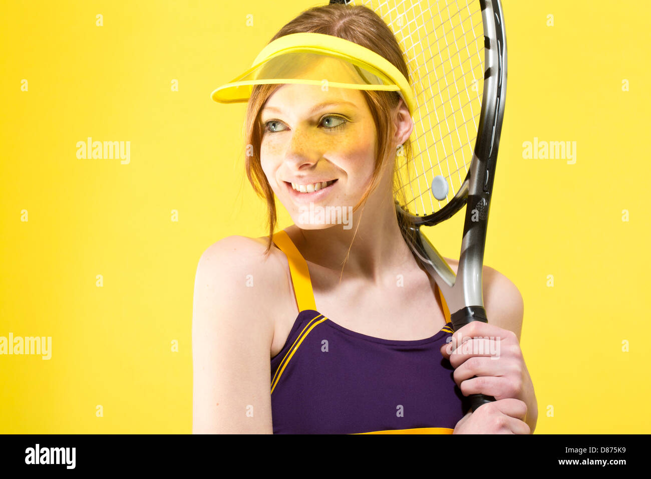 Young woman holding tennis racket against yellow background, smiling ...