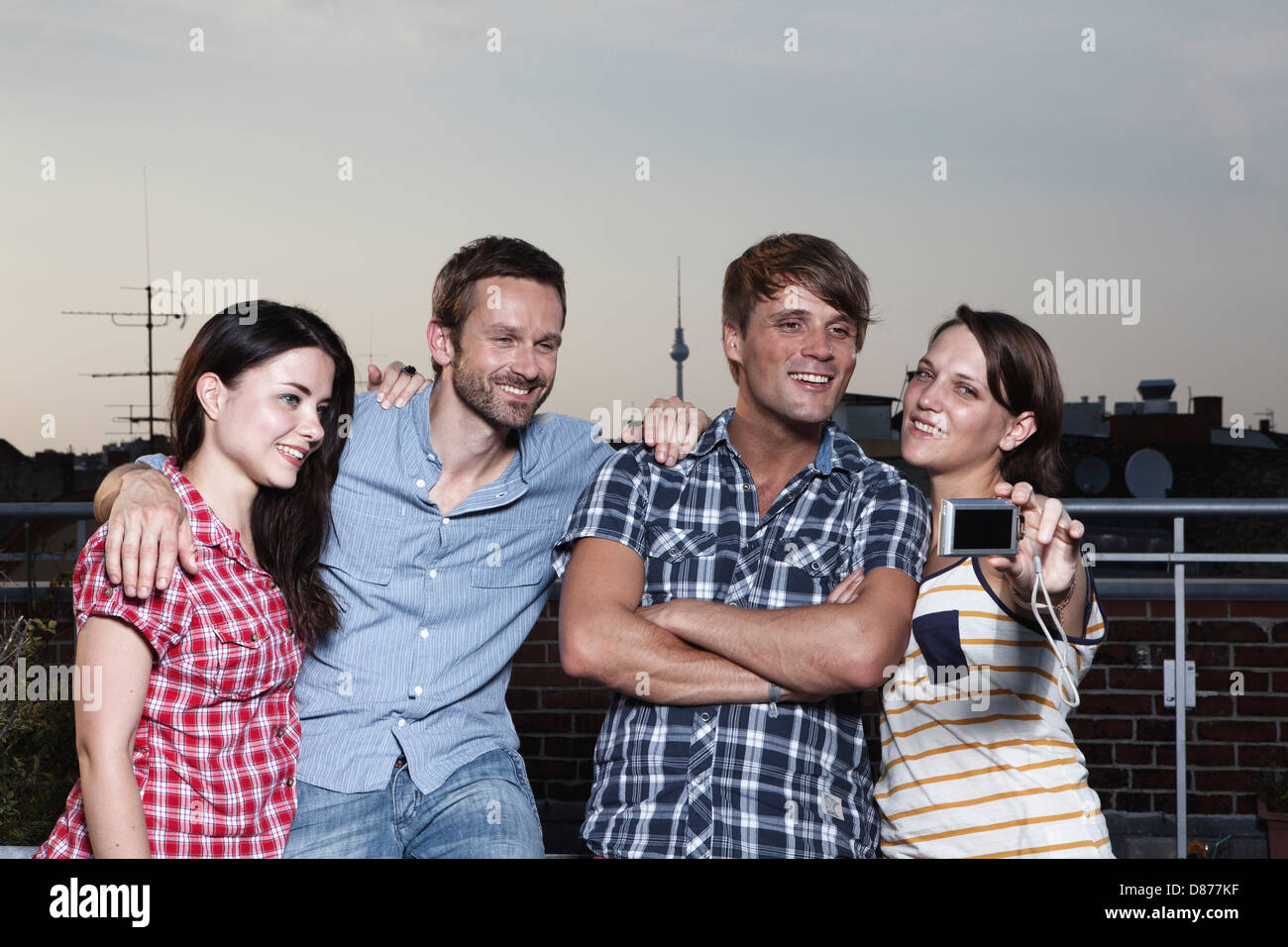 Germany, Berlin, Group of friends taking self photograph on roof ...